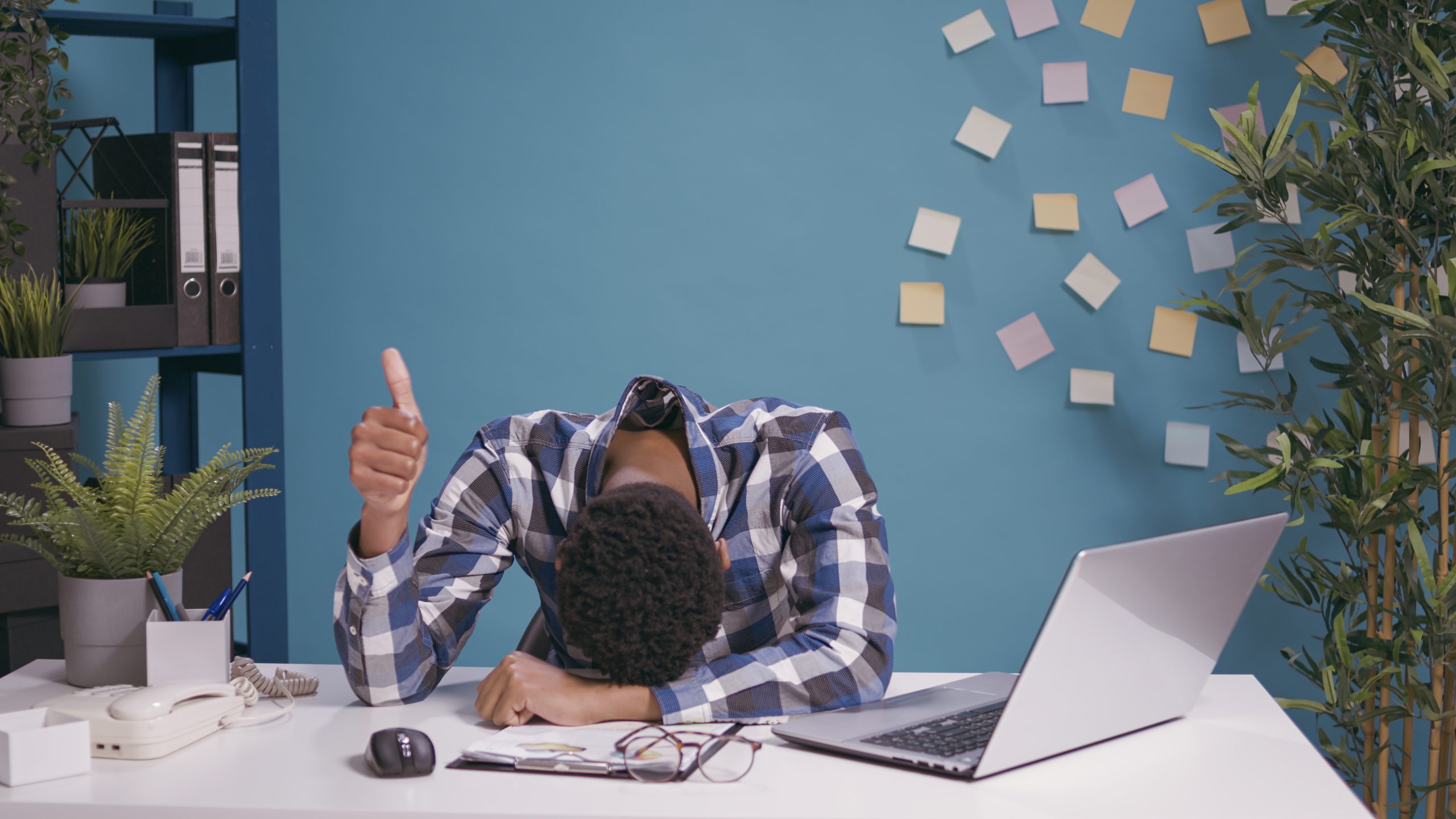 Exhausted worker putting head on desk and showing thumbs up sign | KCI ...